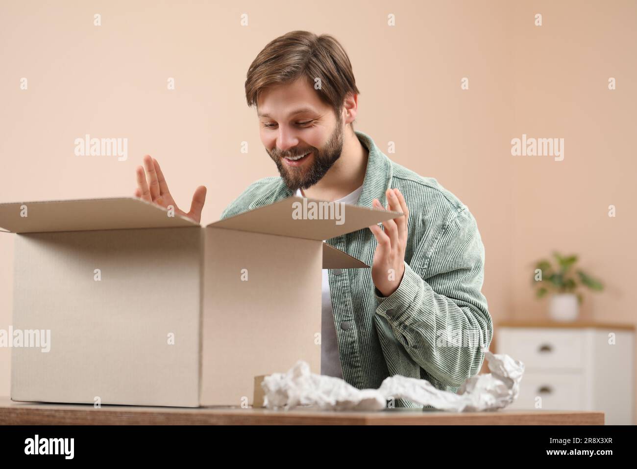 Happy man opening parcel at home. Internet shopping Stock Photo - Alamy