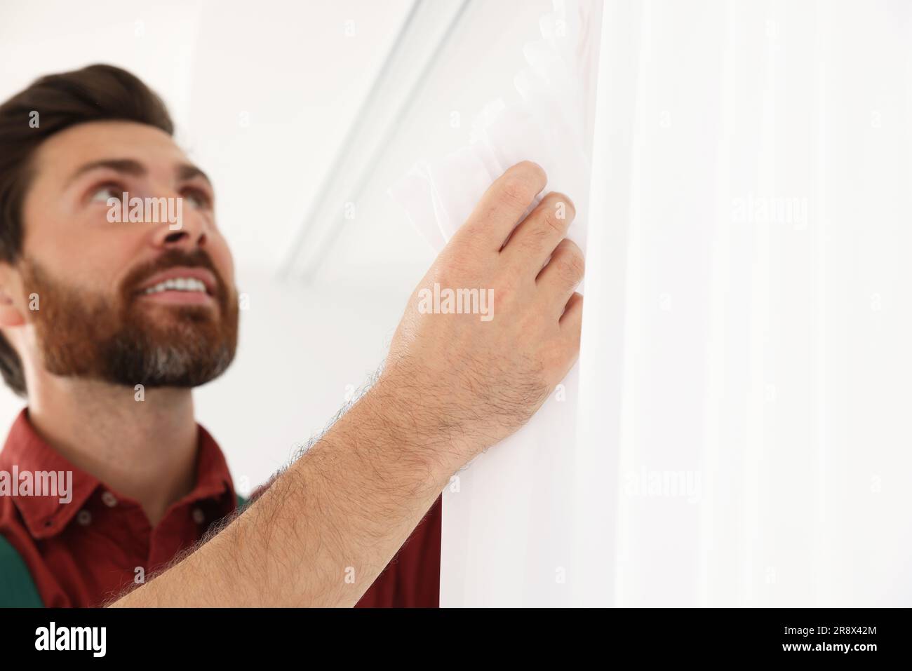 Worker in uniform hanging window curtain indoors, focus on hand Stock ...