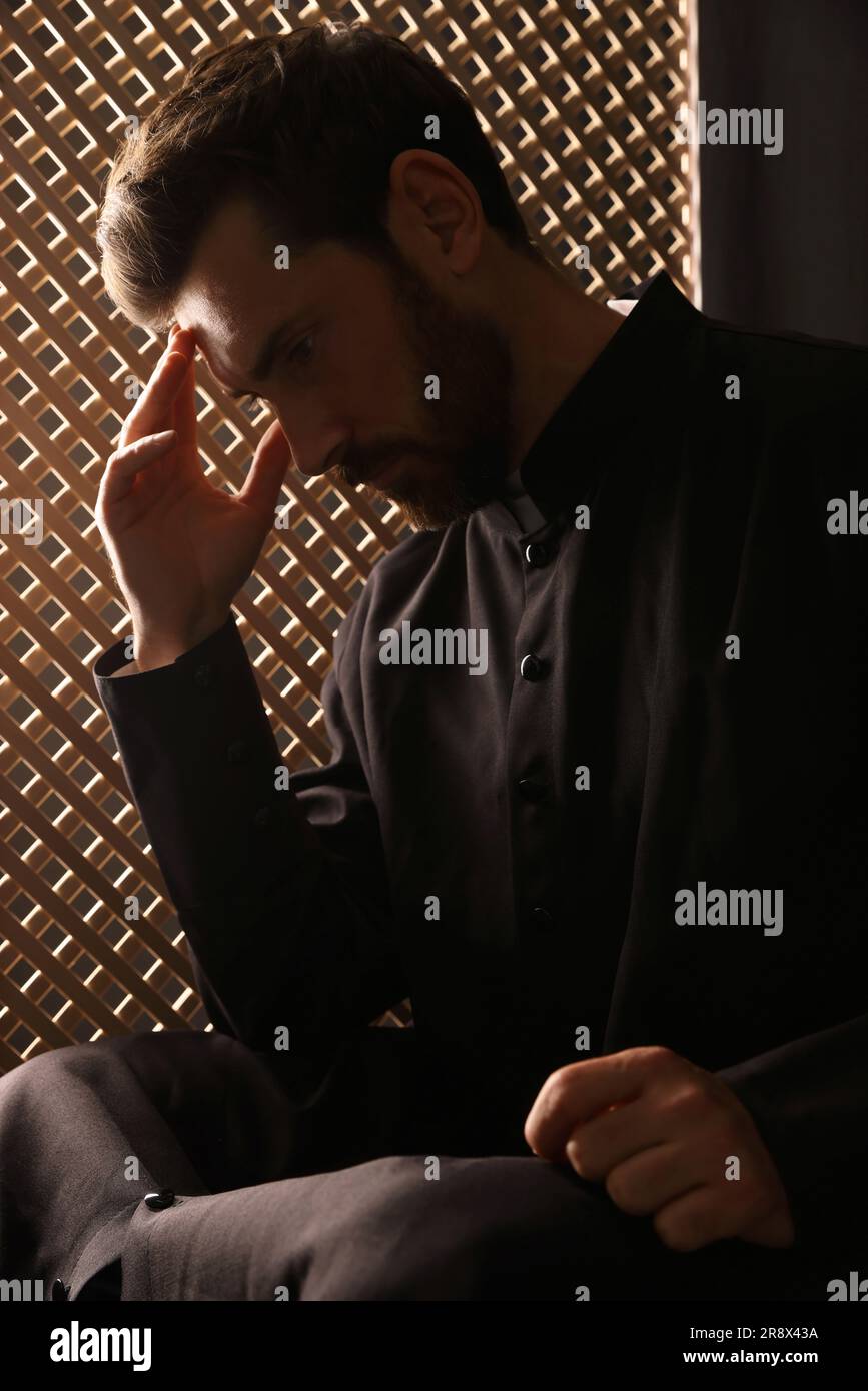 Catholic priest wearing cassock in confessional booth Stock Photo - Alamy