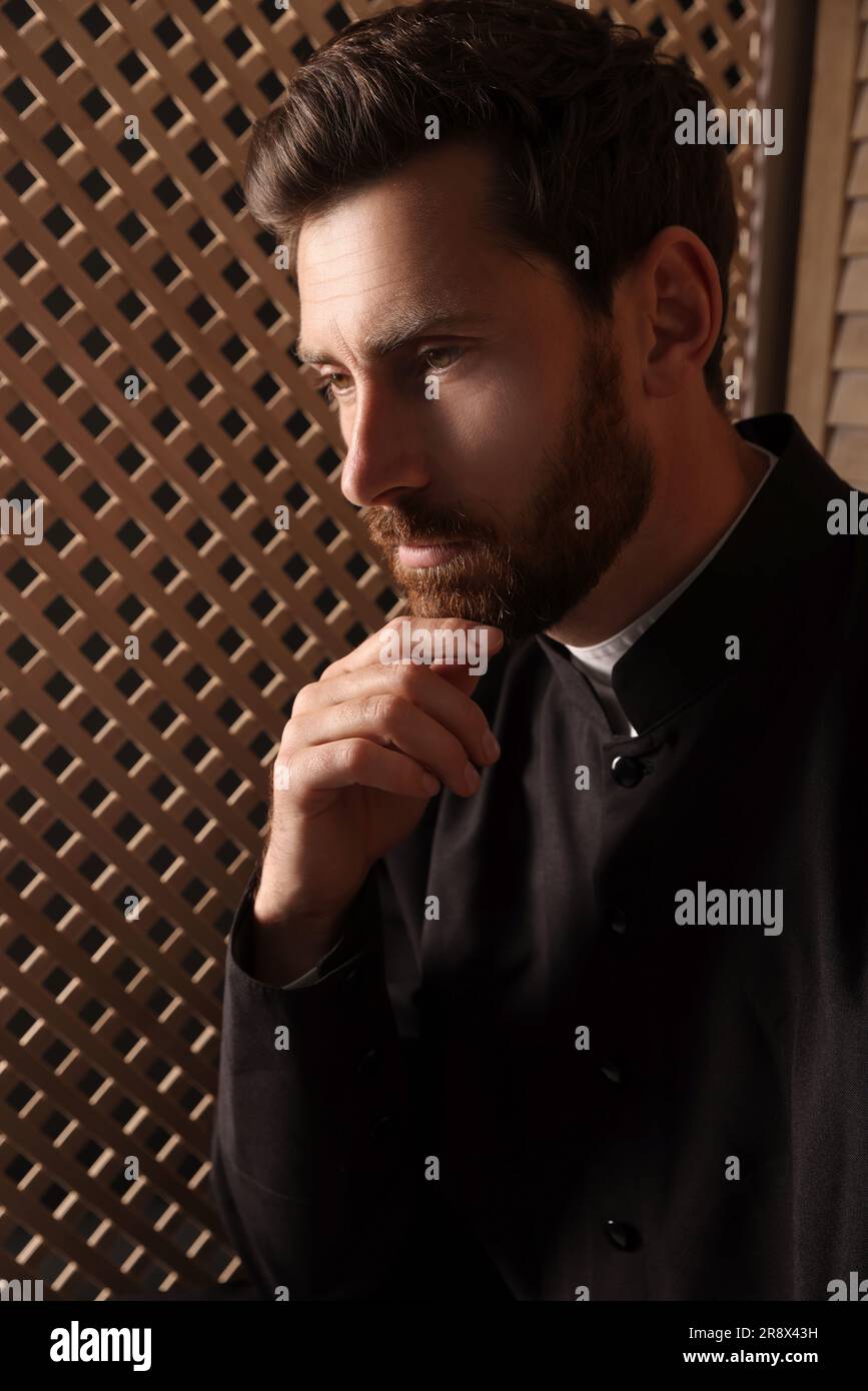 Catholic priest wearing cassock in confessional booth Stock Photo - Alamy