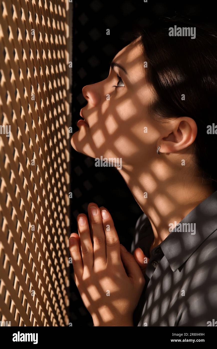 Woman praying to God during confession in booth Stock Photo - Alamy