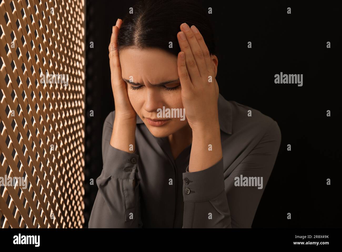 Repentant woman during confession near wooden partition in booth Stock ...
