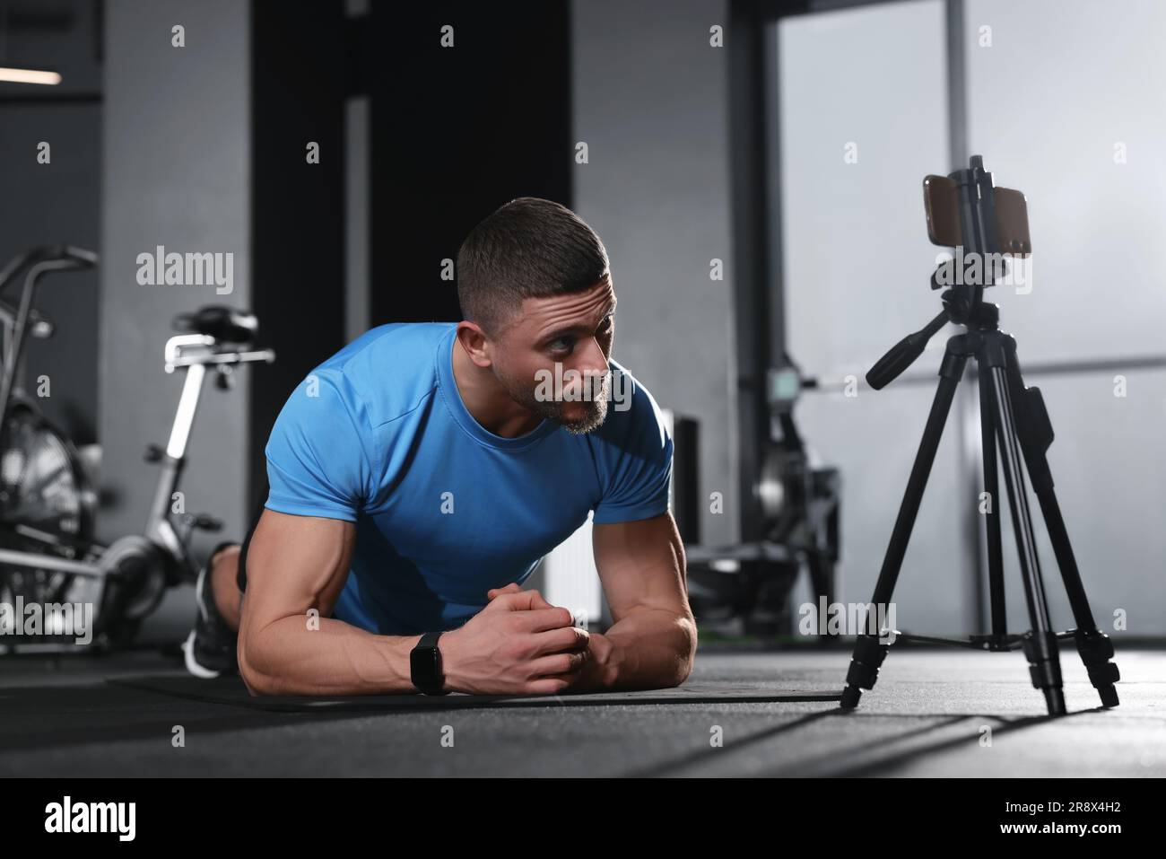 Trainer streaming online workout with phone at gym Stock Photo - Alamy
