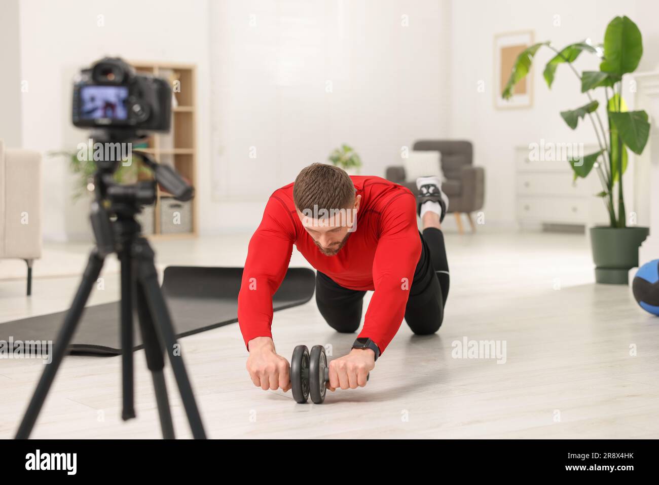 Trainer with ab wheel recording workout on camera at home Stock Photo ...