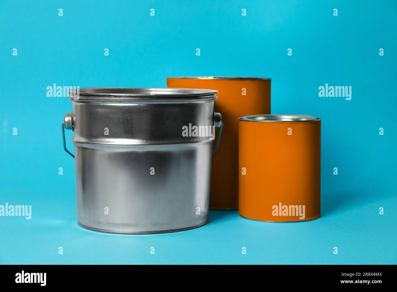 Cans and bucket of orange paint on turquoise background Stock Photo - Alamy