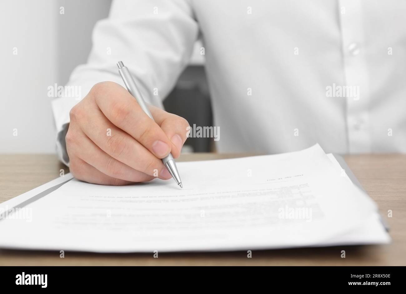 Man signing document at wooden table, closeup Stock Photo - Alamy