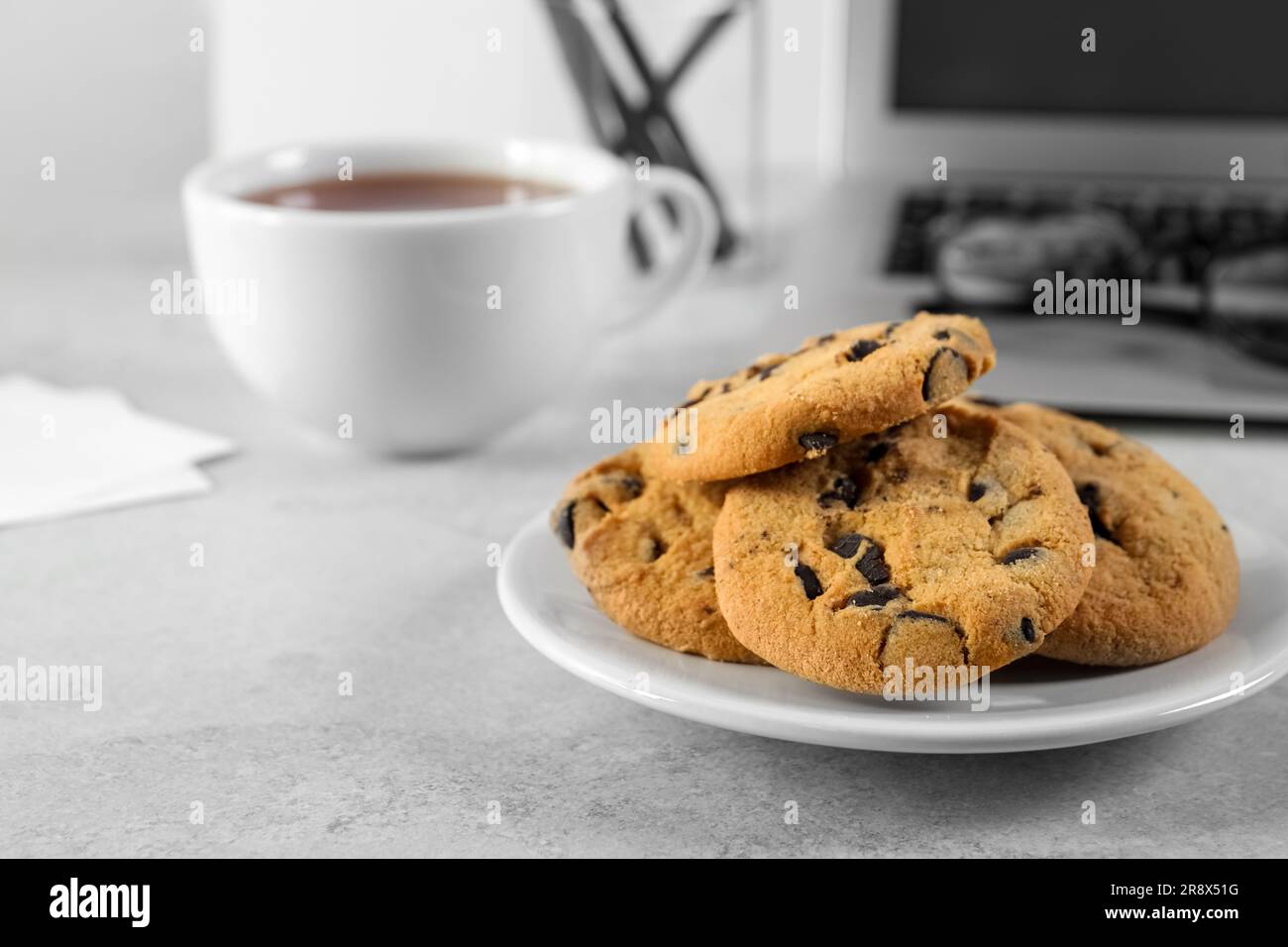 Chocolate chip cookies on light gray table at workplace, space for text ...