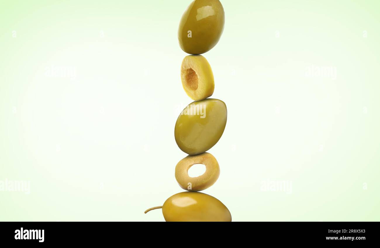 Cut and whole olives on light green gradient background Stock Photo - Alamy