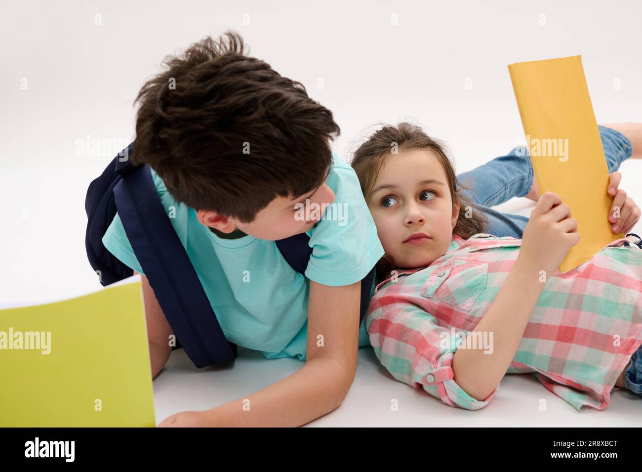 Authentic school kids, little girl and teen boy look at each other ...