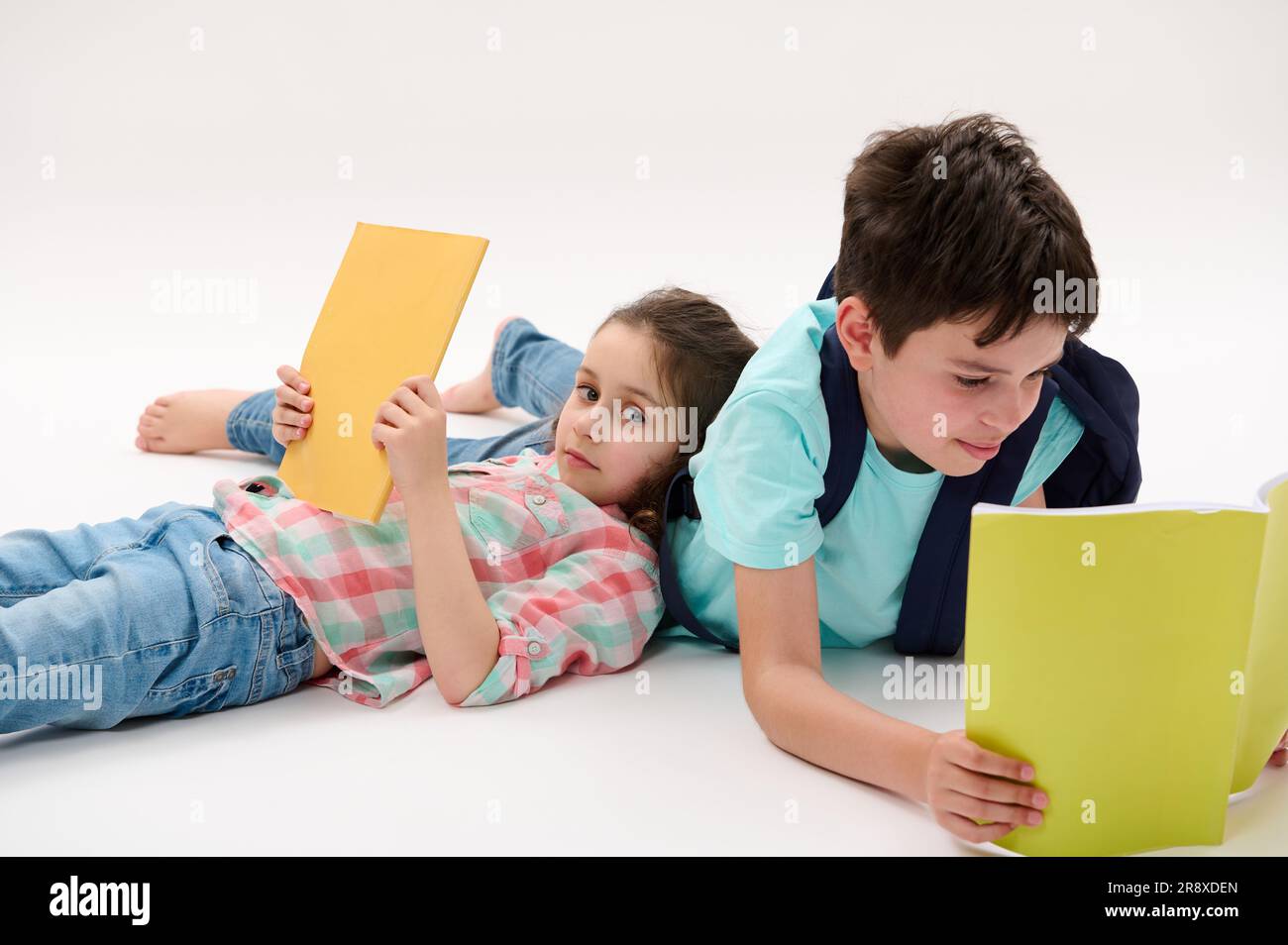 Two charming school kids with backpacks, lying on a white background ...