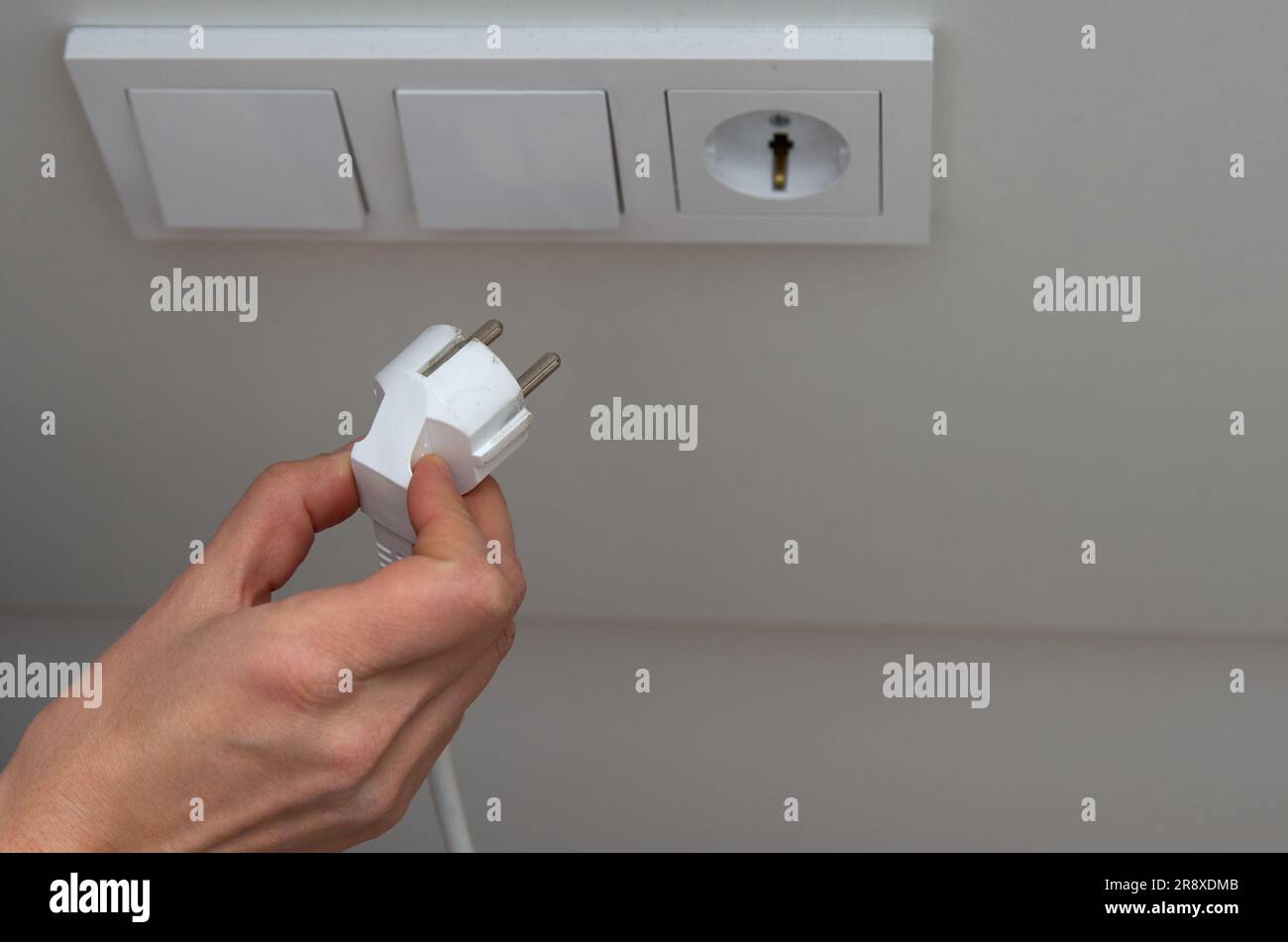 Woman's hand plugs an electric plug into a socket Stock Photo - Alamy