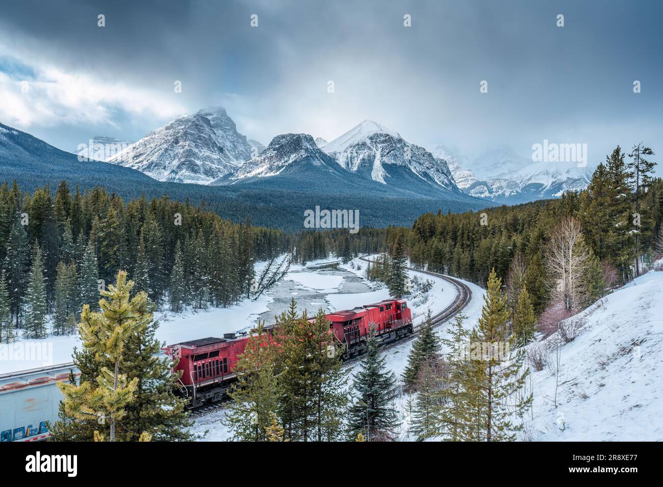Viewpoint of Morants Curve with iconic red cargo train passing through bow valley and rocky ...