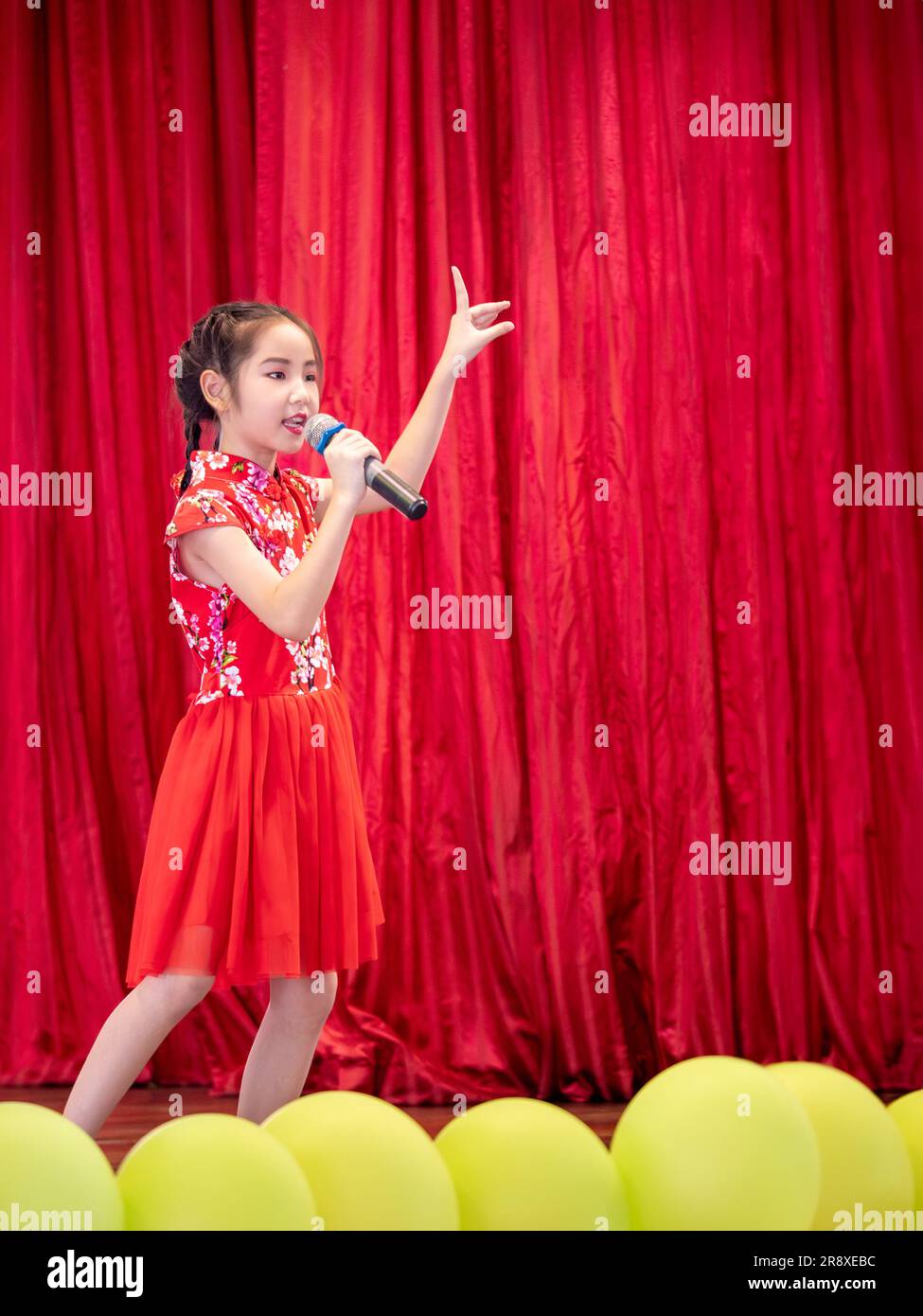 The Asian kid girl sing a song on stage at her school activity day ...