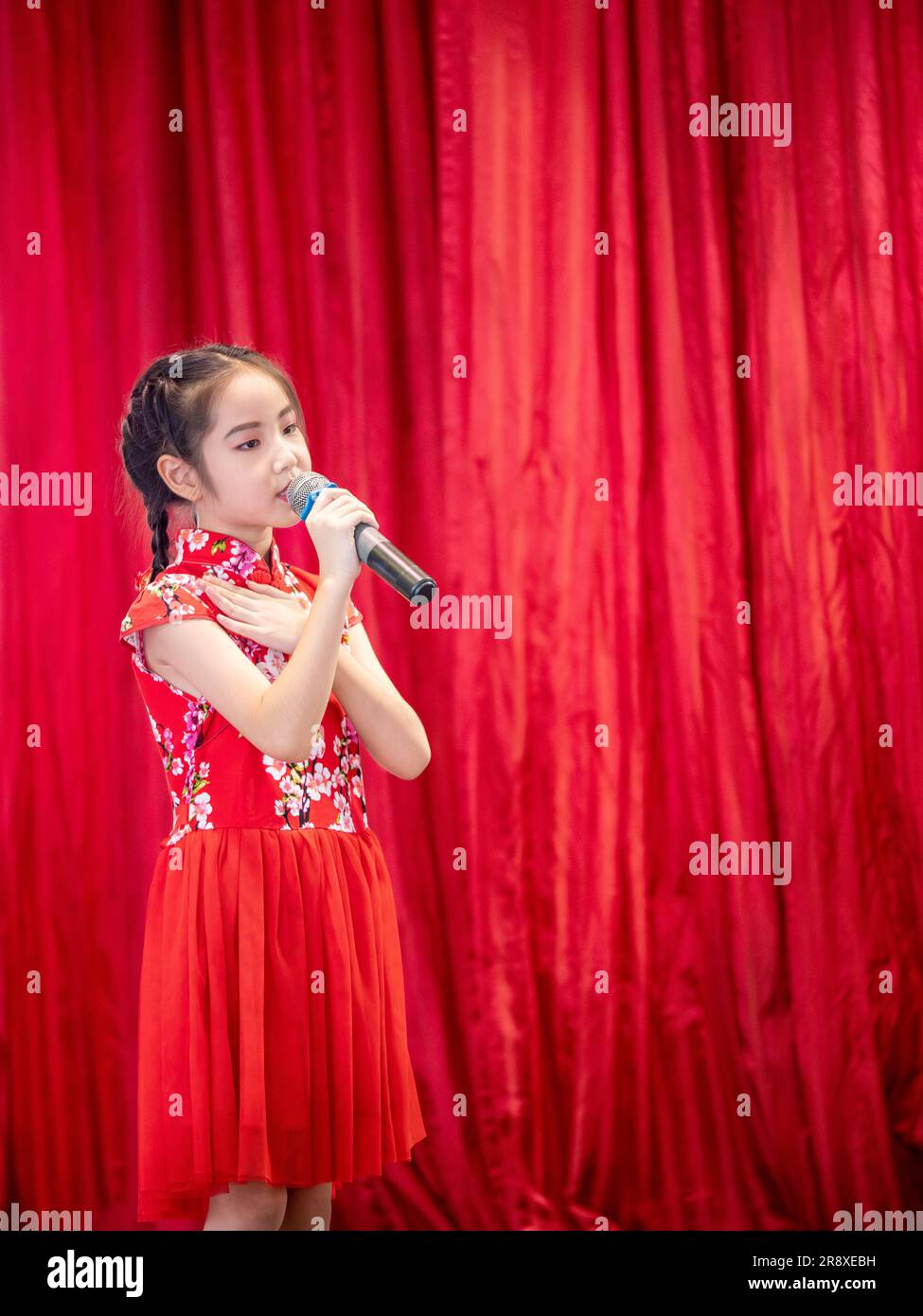 The Asian kid girl sing a song on stage at her school activity day ...