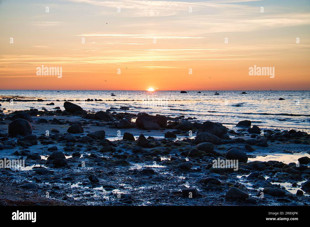 Sunset, stone beach with small and large rocks in front of the ...