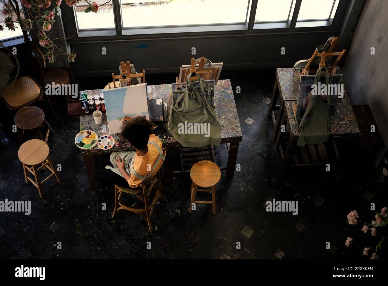 Overhead view of inspired female artist painting picture on canvas ...