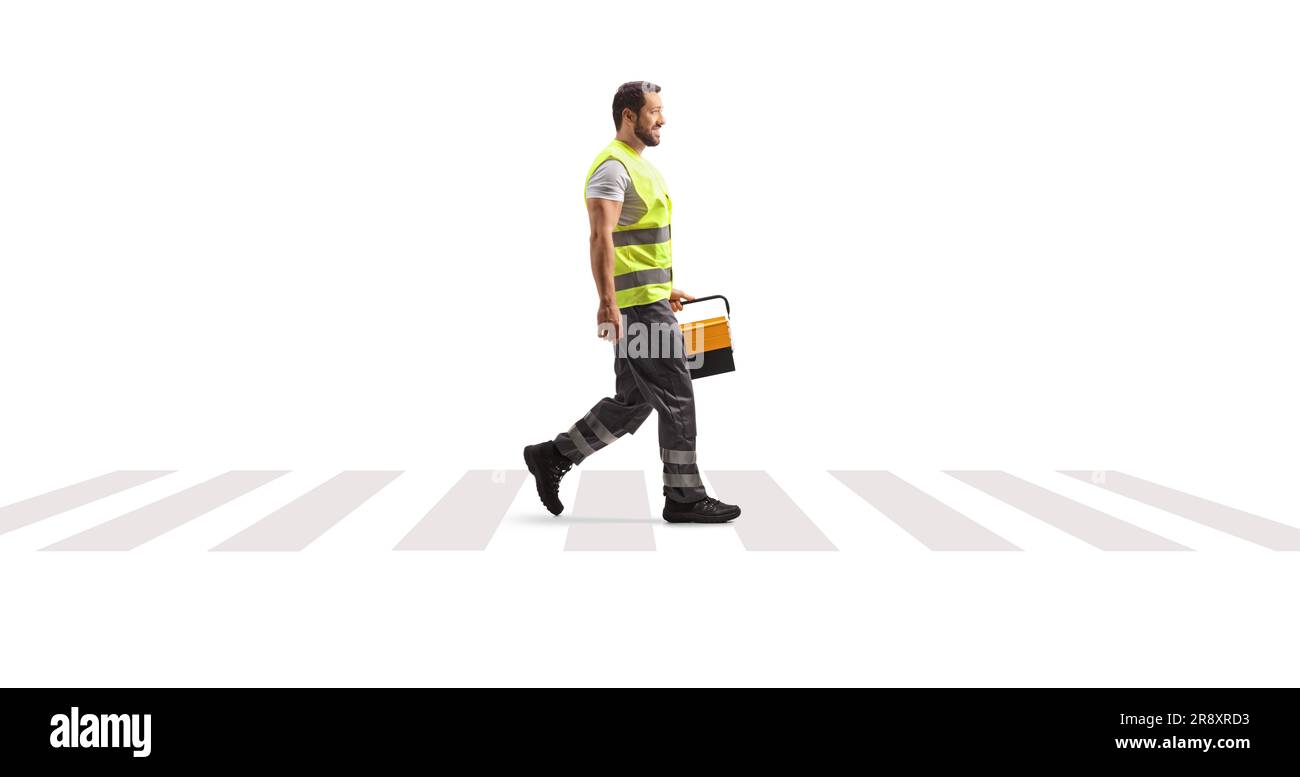 Road assistance mechanic walking at a pedestrian crosswalk and carrying ...