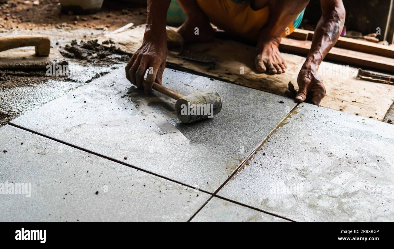 A male construction worker installs a large ceramic tile Stock Photo ...