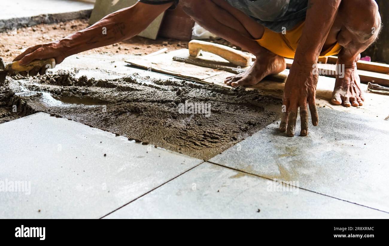 A male construction worker installs a large ceramic tile Stock Photo ...