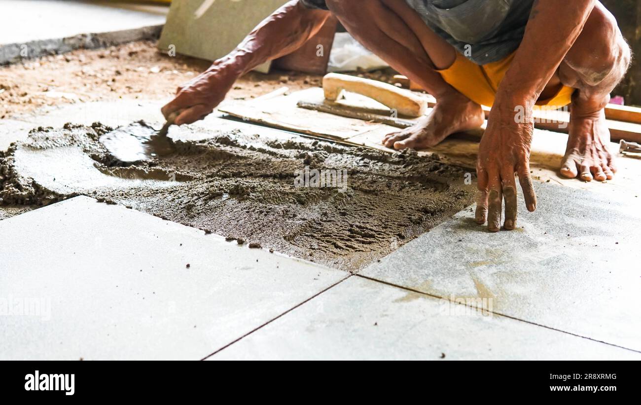 A male construction worker installs a large ceramic tile Stock Photo ...