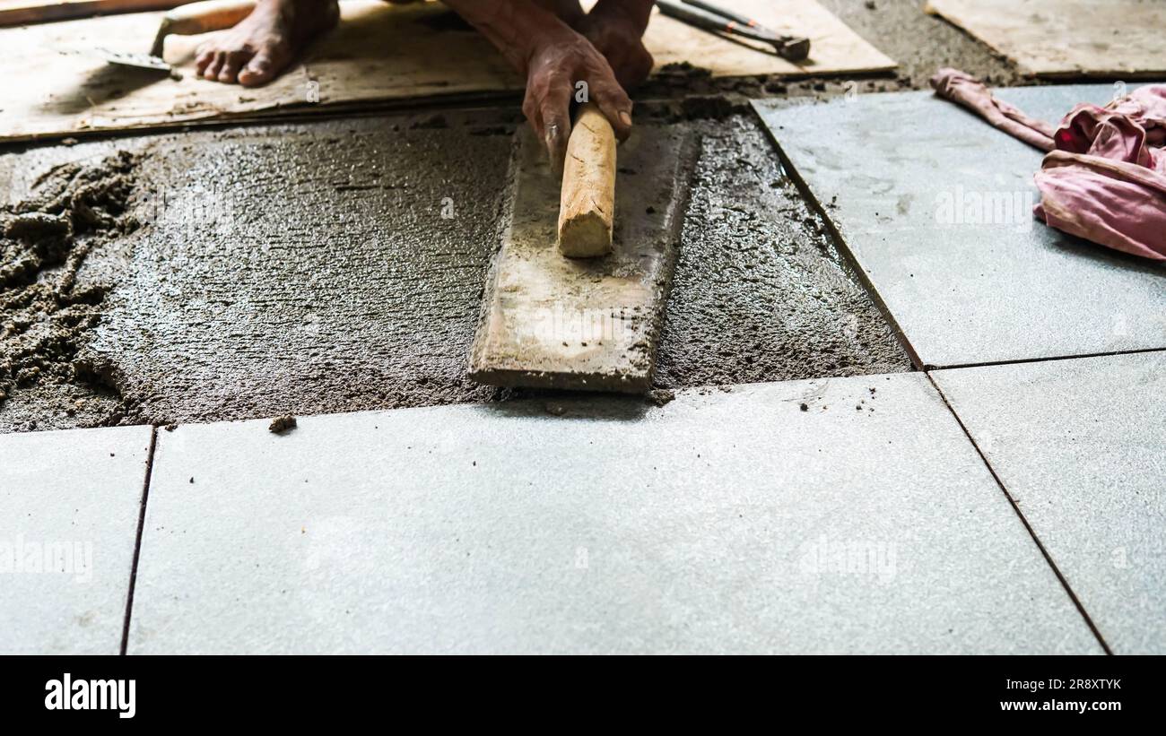 A male construction worker installs a large ceramic tile Stock Photo ...