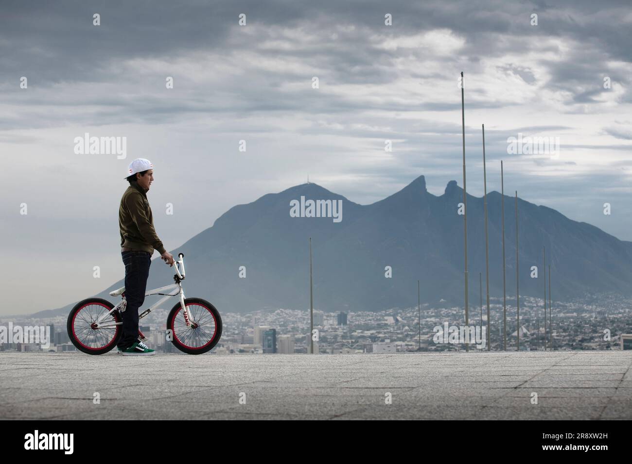 A man with his bike watches a city from a panoramic view point ...