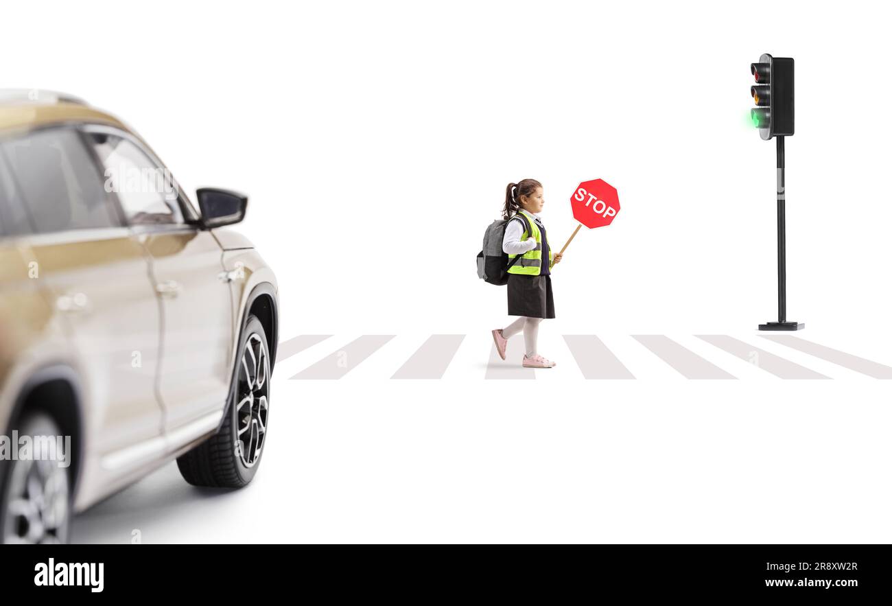 Schoolgirl holding a stop sign in front of a car and crossing a road ...