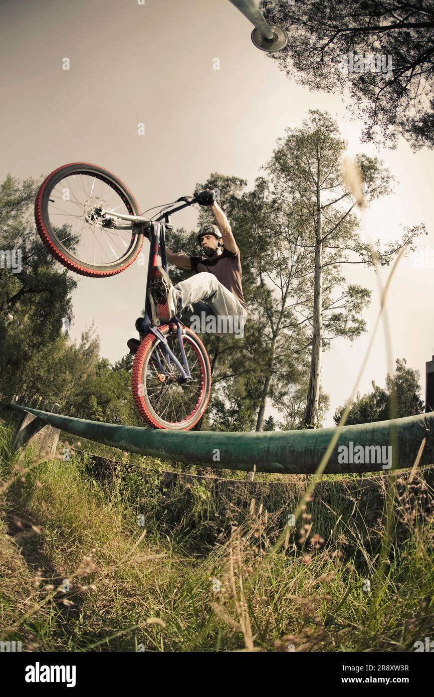 a man with a bike standing on the back wheel of his bike on a green ...
