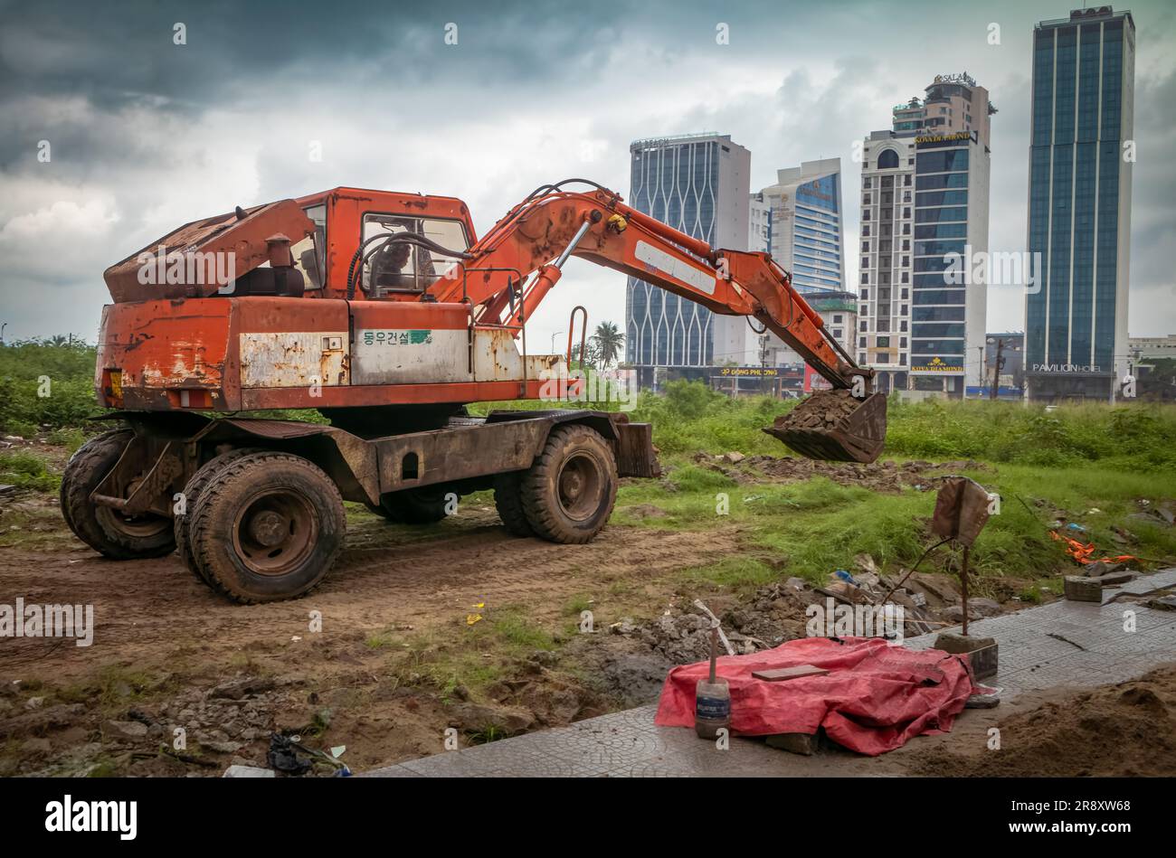 A mechanical digger scrapes a bucket of earth in the rain next to ...