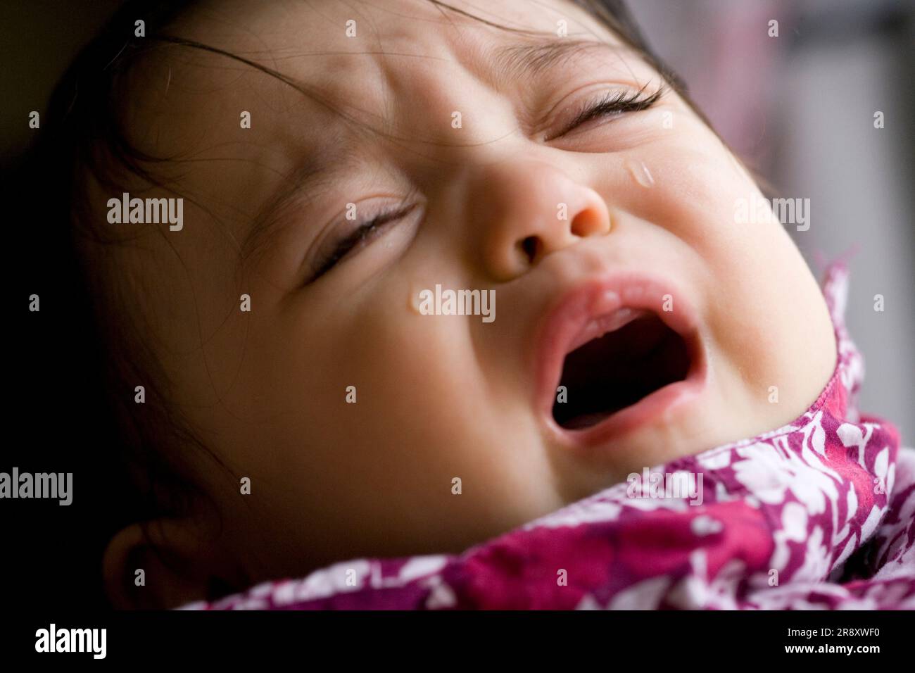 Close up of the face of a crying baby girl with tears streaming down ...