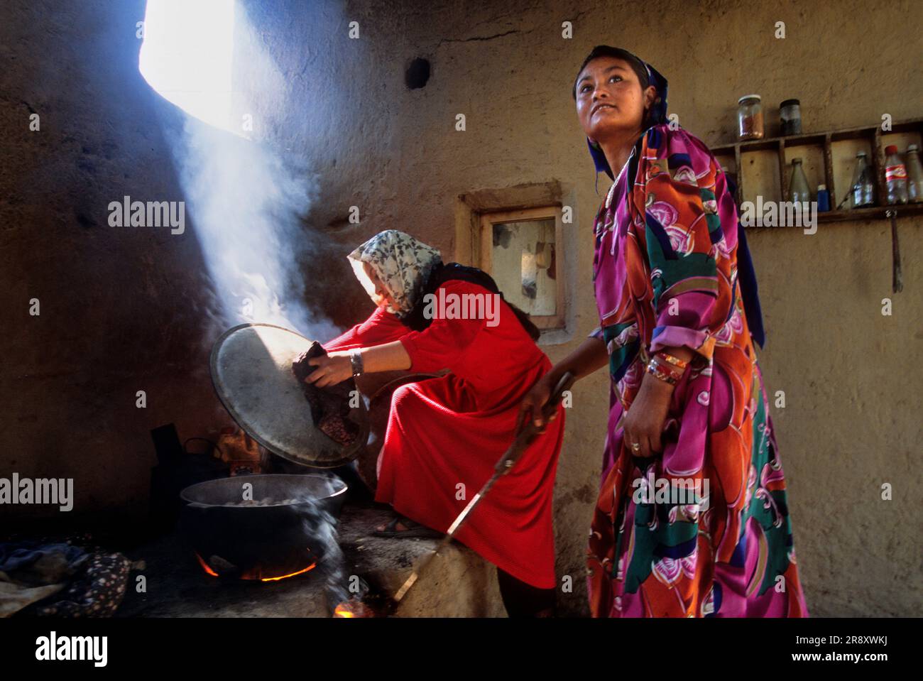 Women cook over an open fire in the kitchen area of a traditional ...