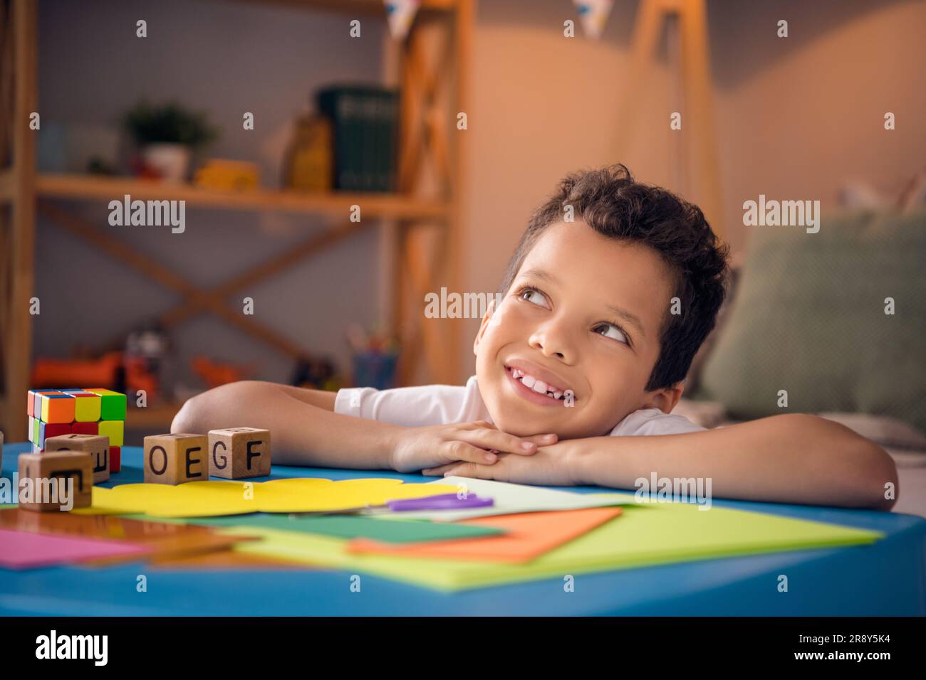 Photo of cute boy lean kid desk in comfort play room thinking dreamy ...