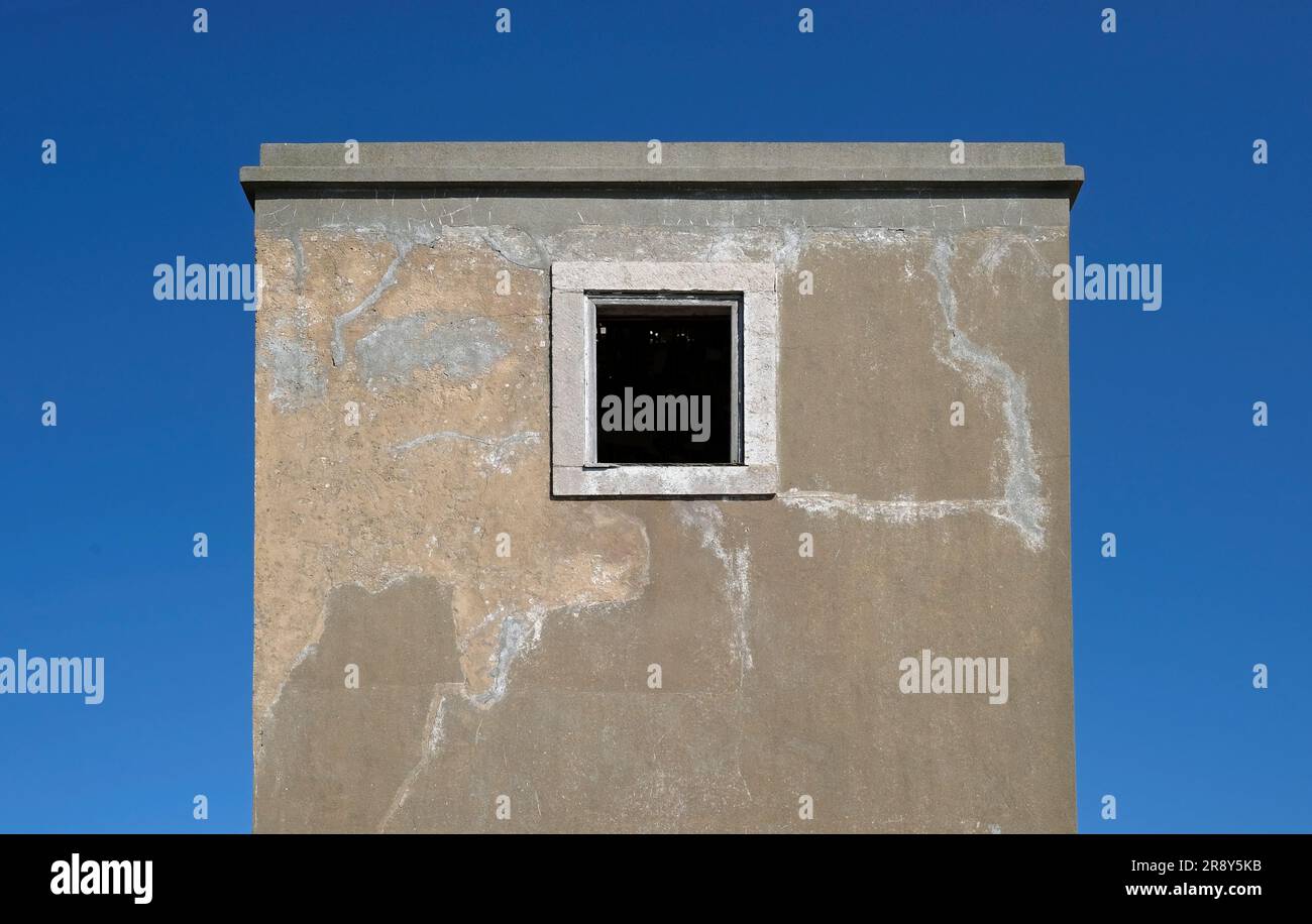 Abandoned building with a single window in the middle against a blue ...