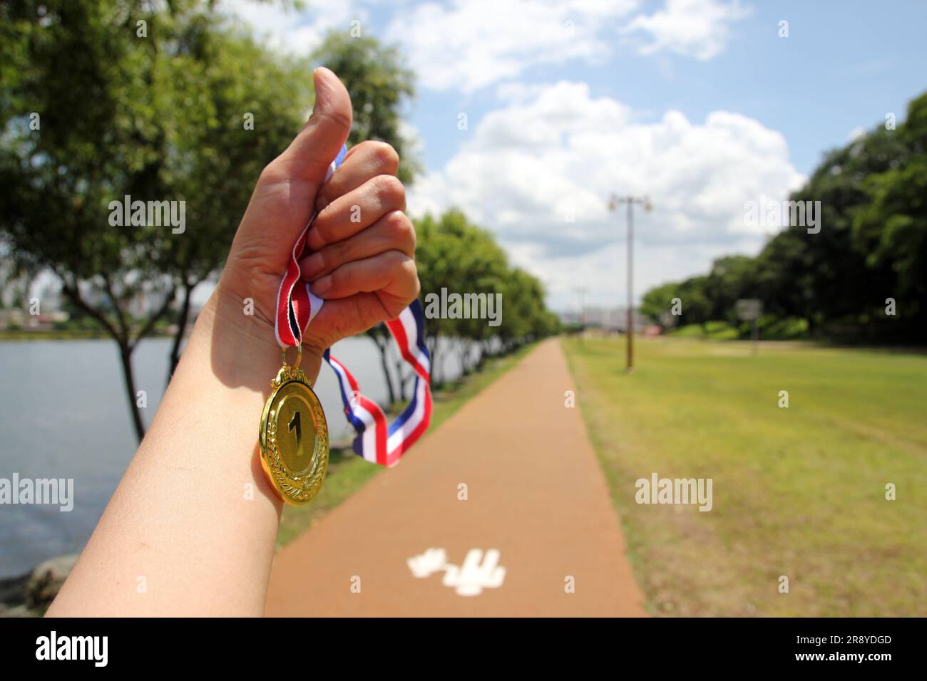 Blurred of woman hands raised and holding gold medals with Thai ribbon ...