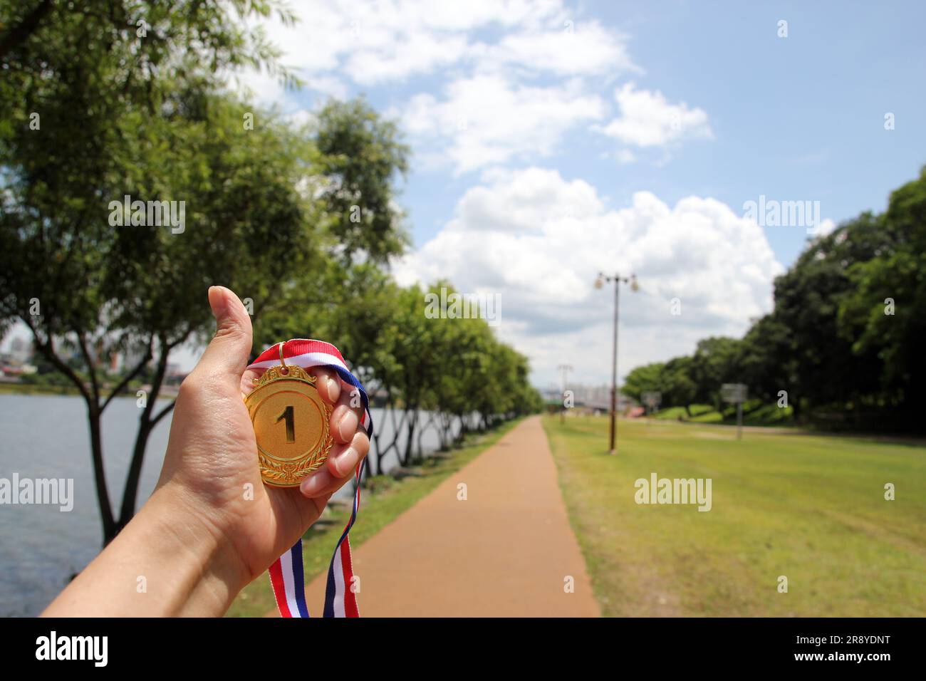 Blurred of woman hands raised and holding gold medals with Thai ribbon ...