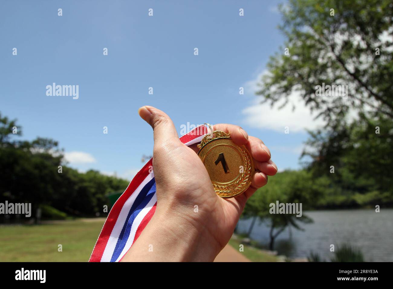 Blurred of woman hands raised and holding gold medals with Thai ribbon ...