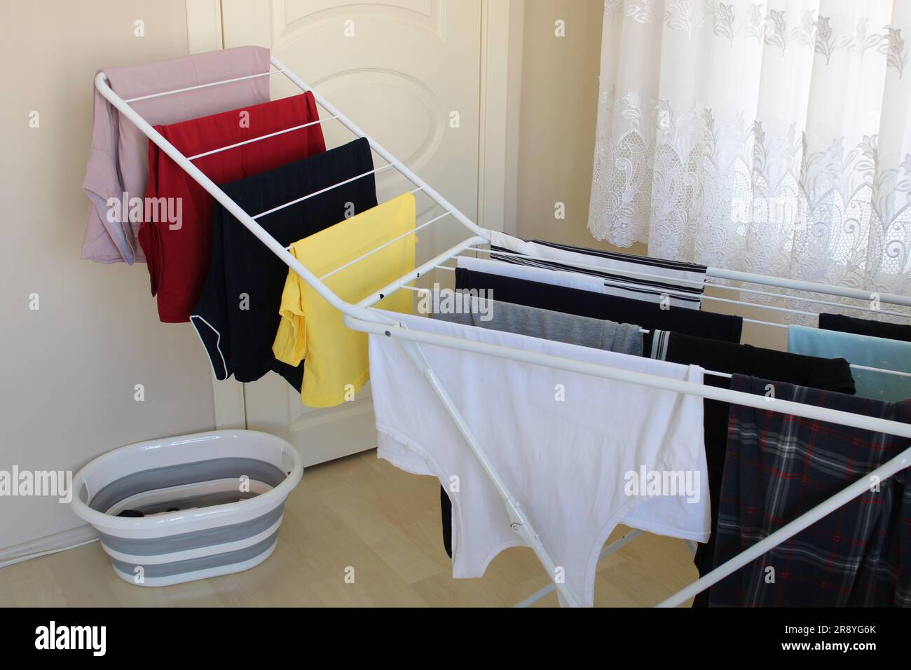 Clean laundry hanging on drying rack in room. Many or lots of washed ...