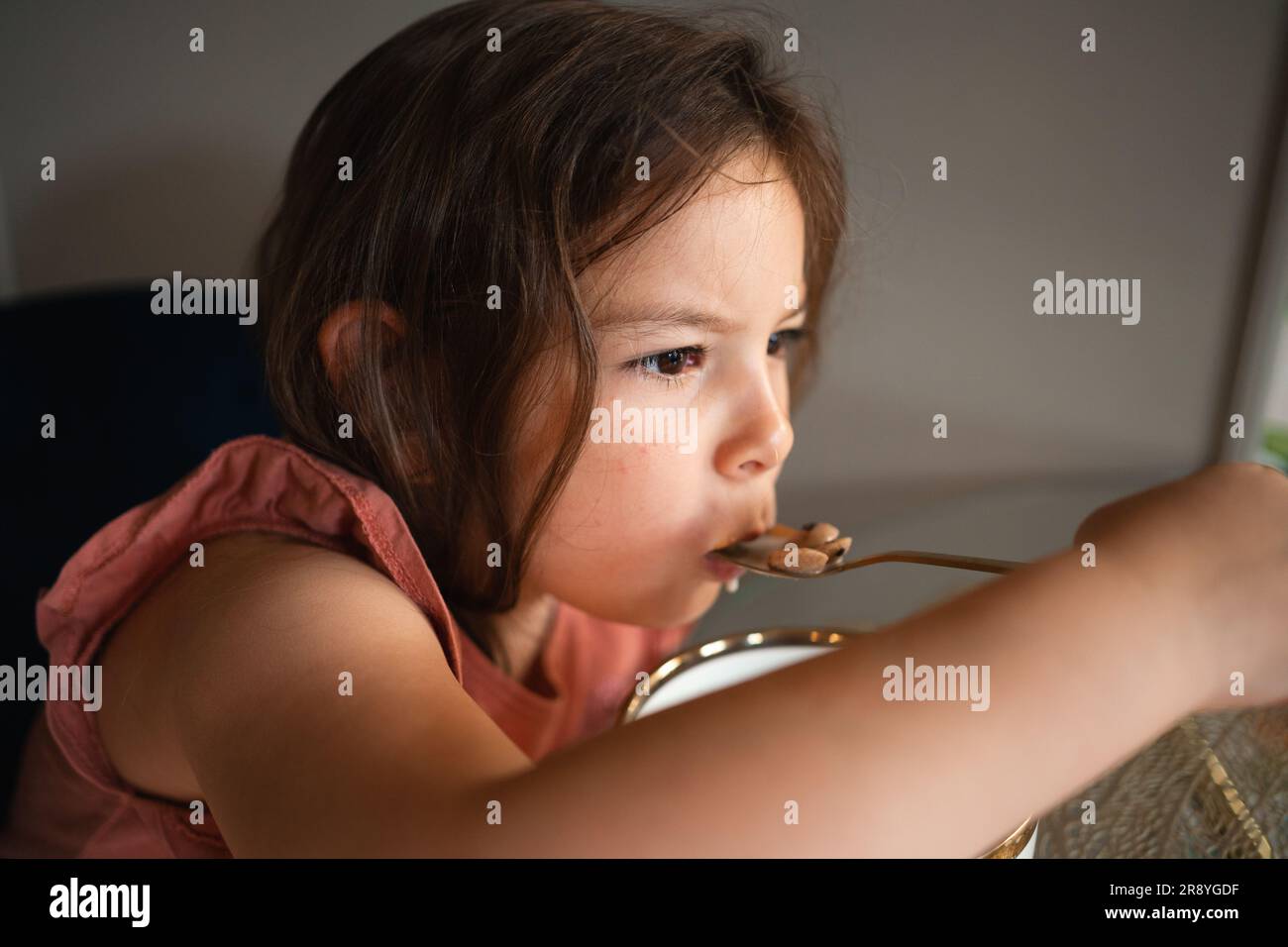 Child girl eating with spoon from the bowl at home Stock Photo - Alamy