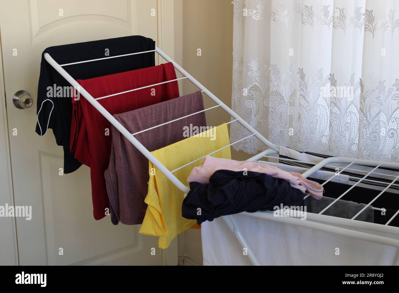 Clean laundry hanging on drying rack in room. Many or lots of washed ...