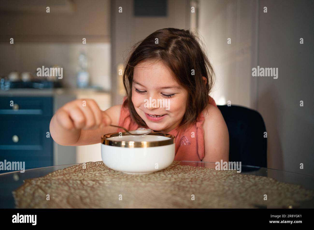 Child girl eating with spoon from the bowl at home Stock Photo - Alamy