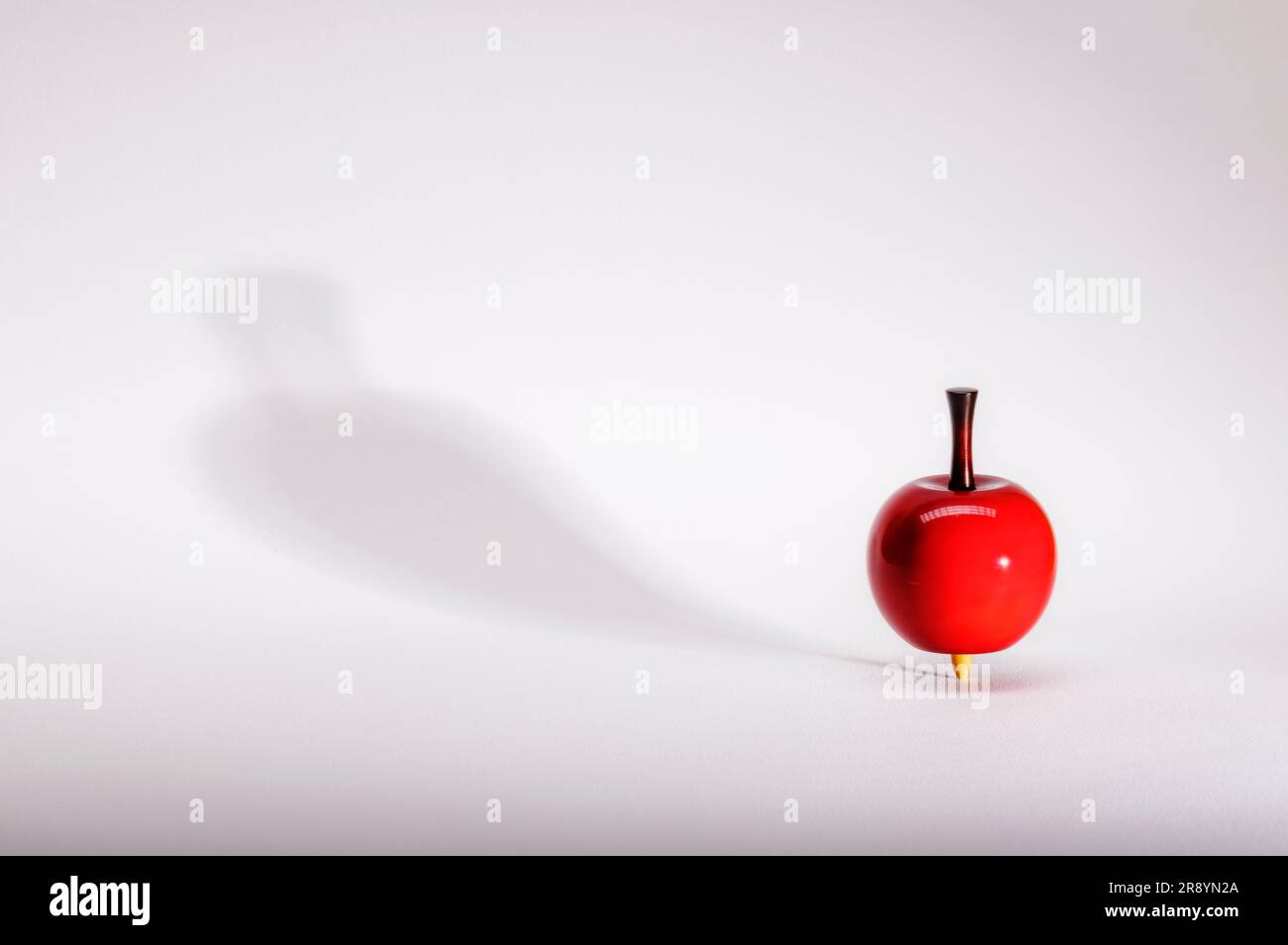 An apple-shaped spinning top with its shadow isolated on white ...
