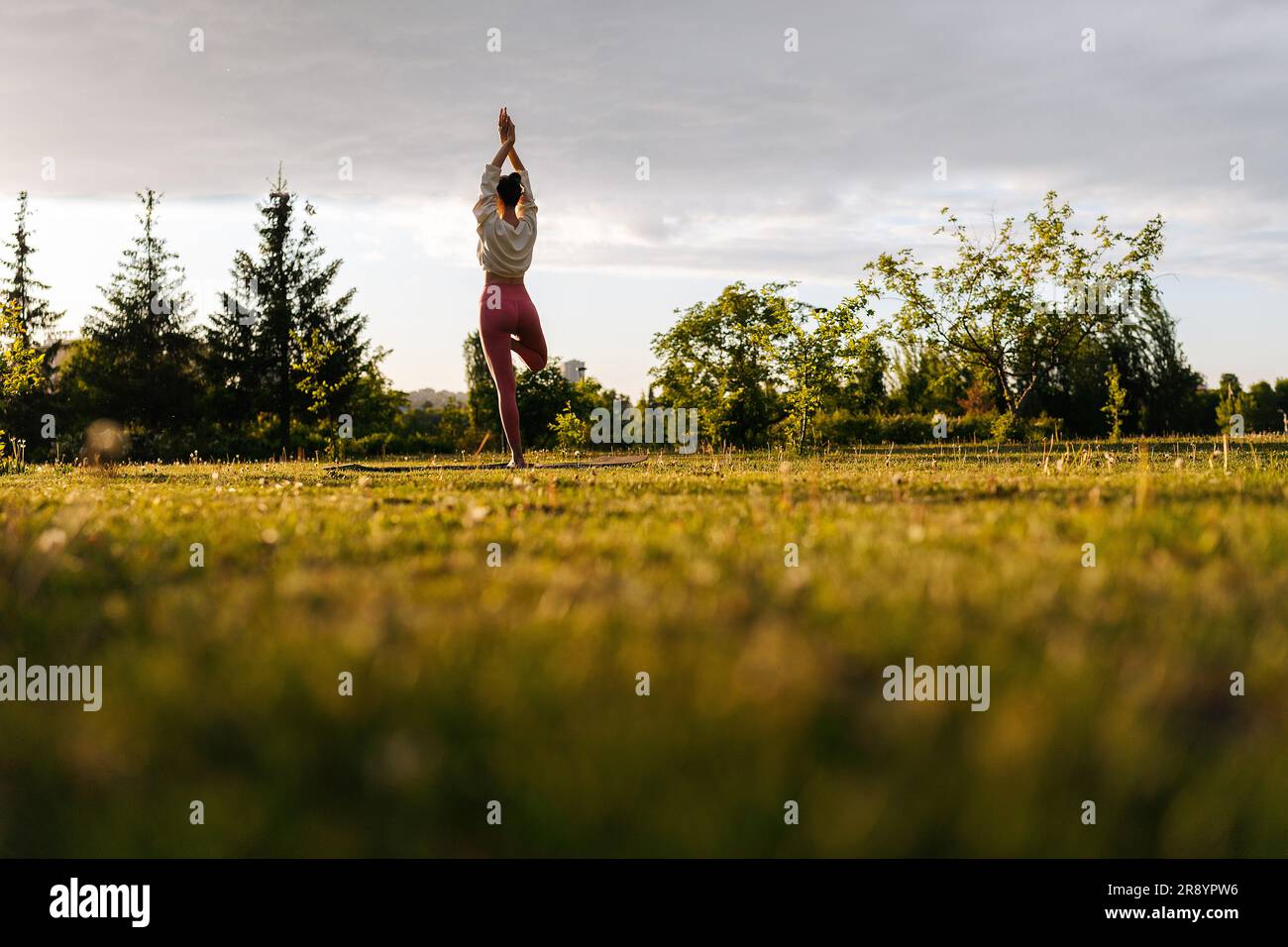 Low-angle back view of unrecognizable meditative young woman in white ...