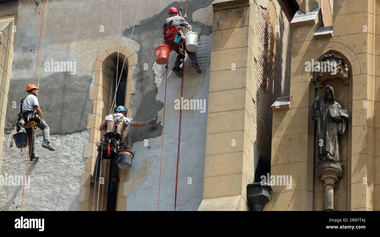 High-altitude workers (climbers) hanging on ropes repair the towers of ...