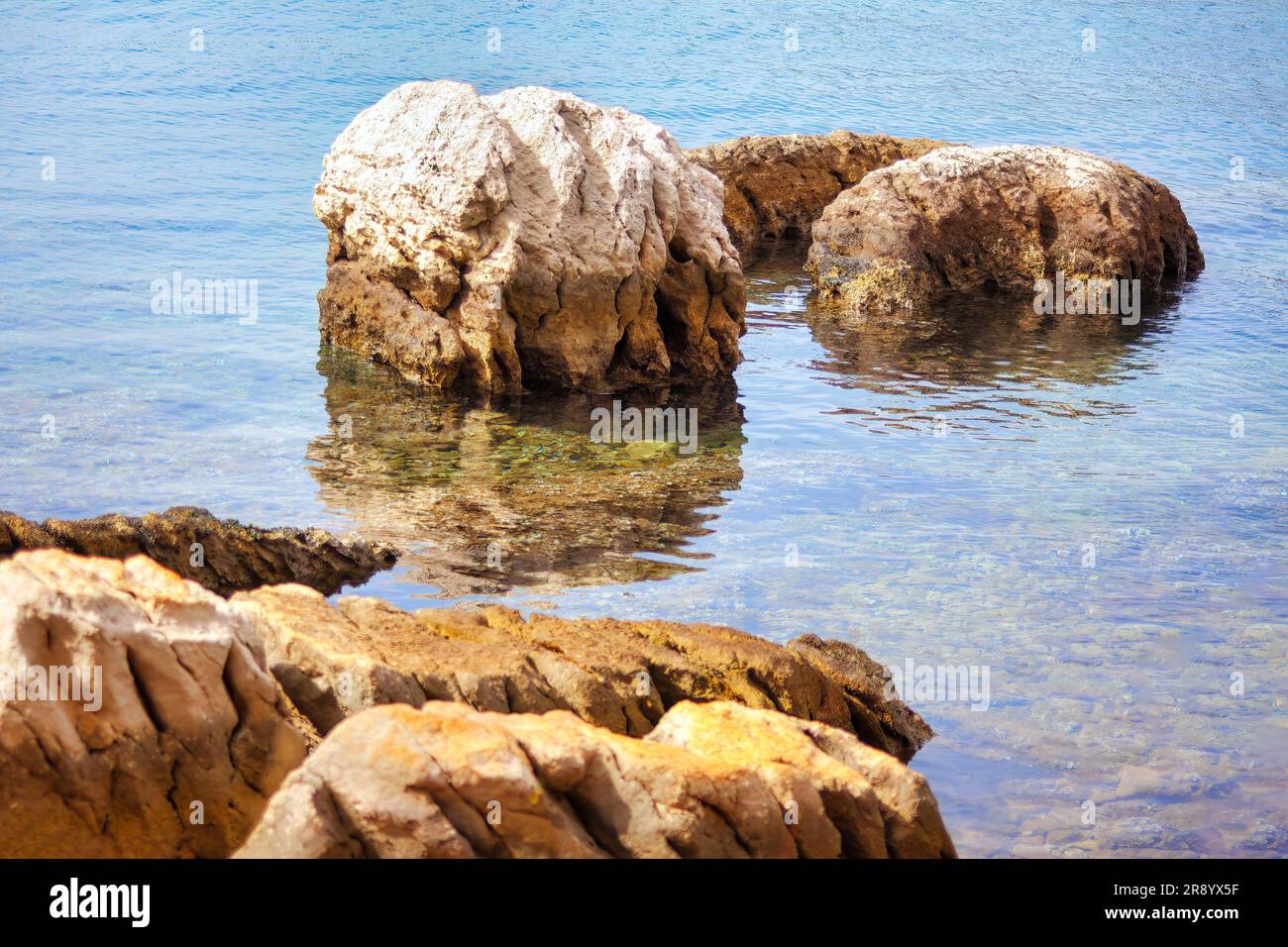 Rocks in the sea . Still and calm sea water with big stones Stock Photo ...