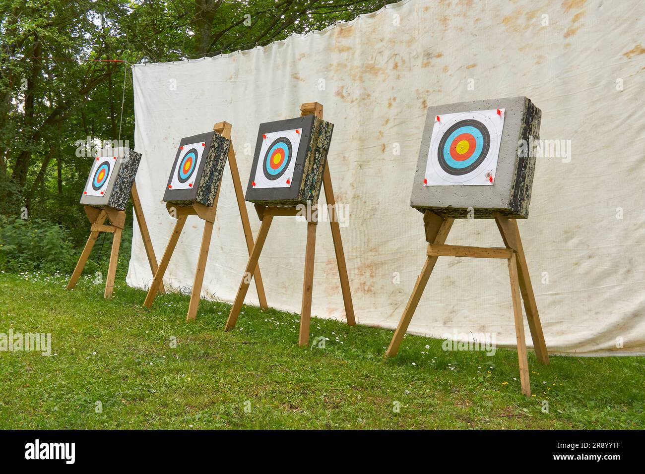 Four targets in a row for archery in front of a stretched canvas ...