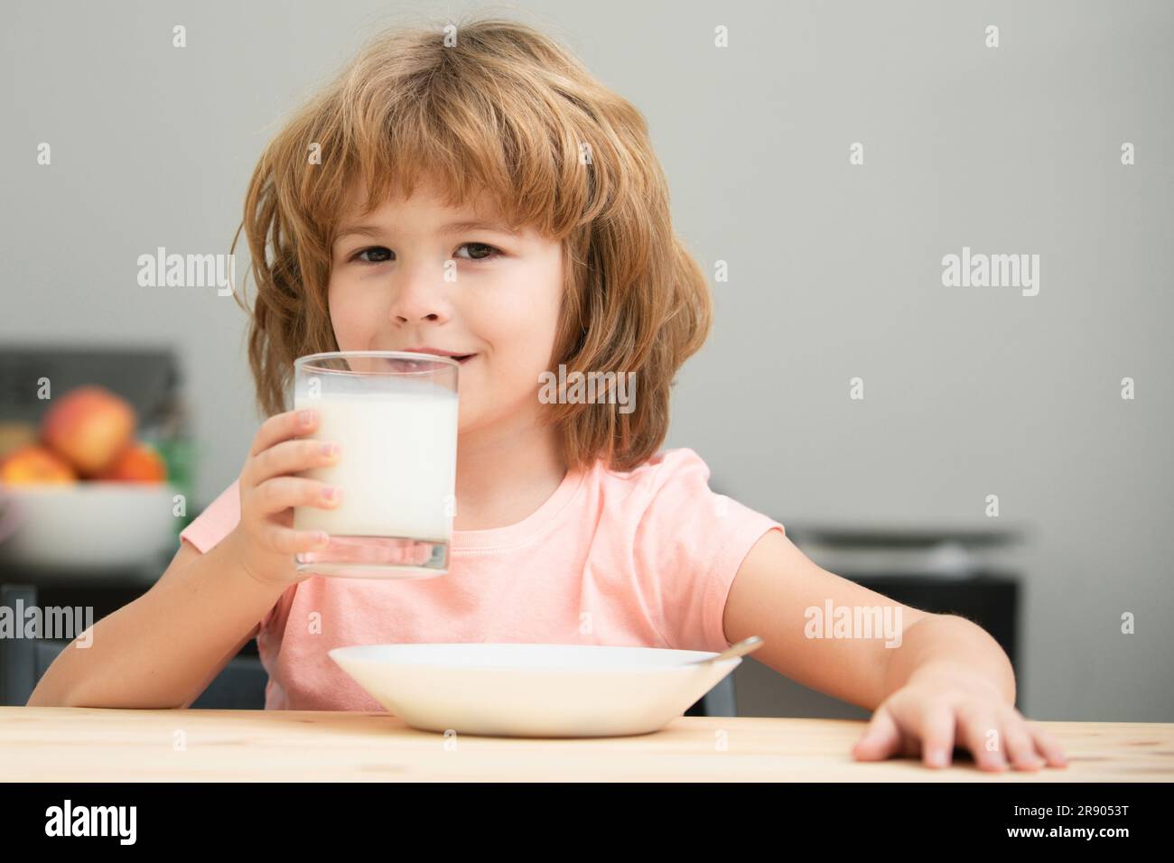 Cute little child with glass of milk at table in kitchen. Kid eating ...