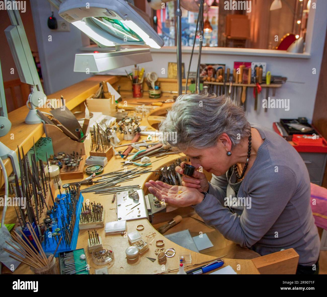 A goldsmith is creating a ring from melted gold. The gold is melted ...