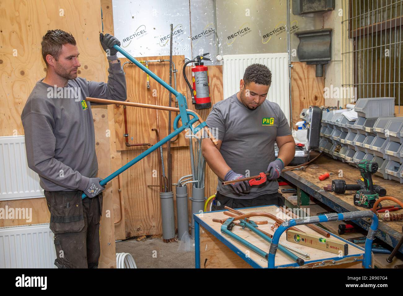 Netherlands, The Hague; plumber is bending a new copper pipe in his ...