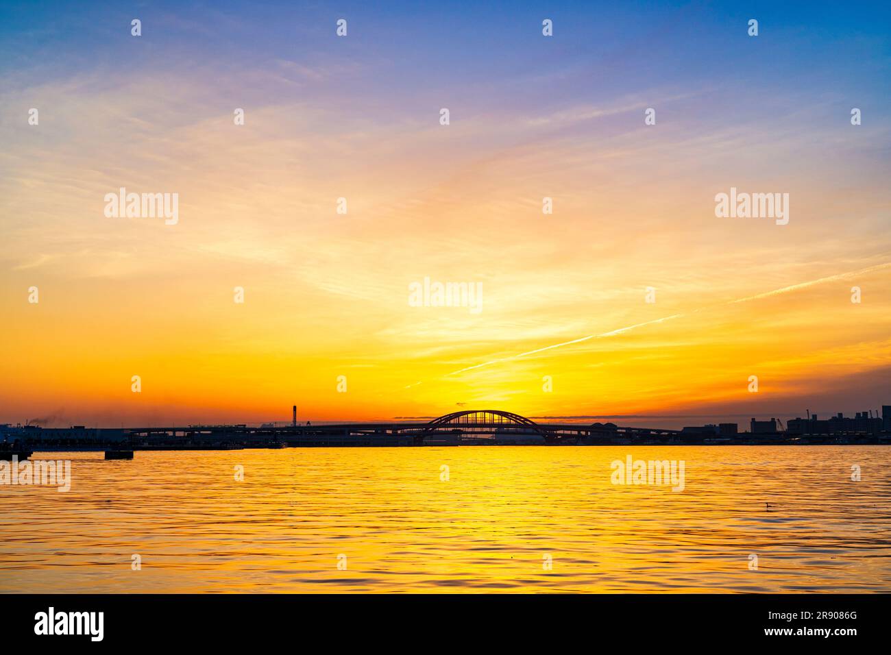 A vivid orange dawn sky behind the silhouette of the double-deck arched ...