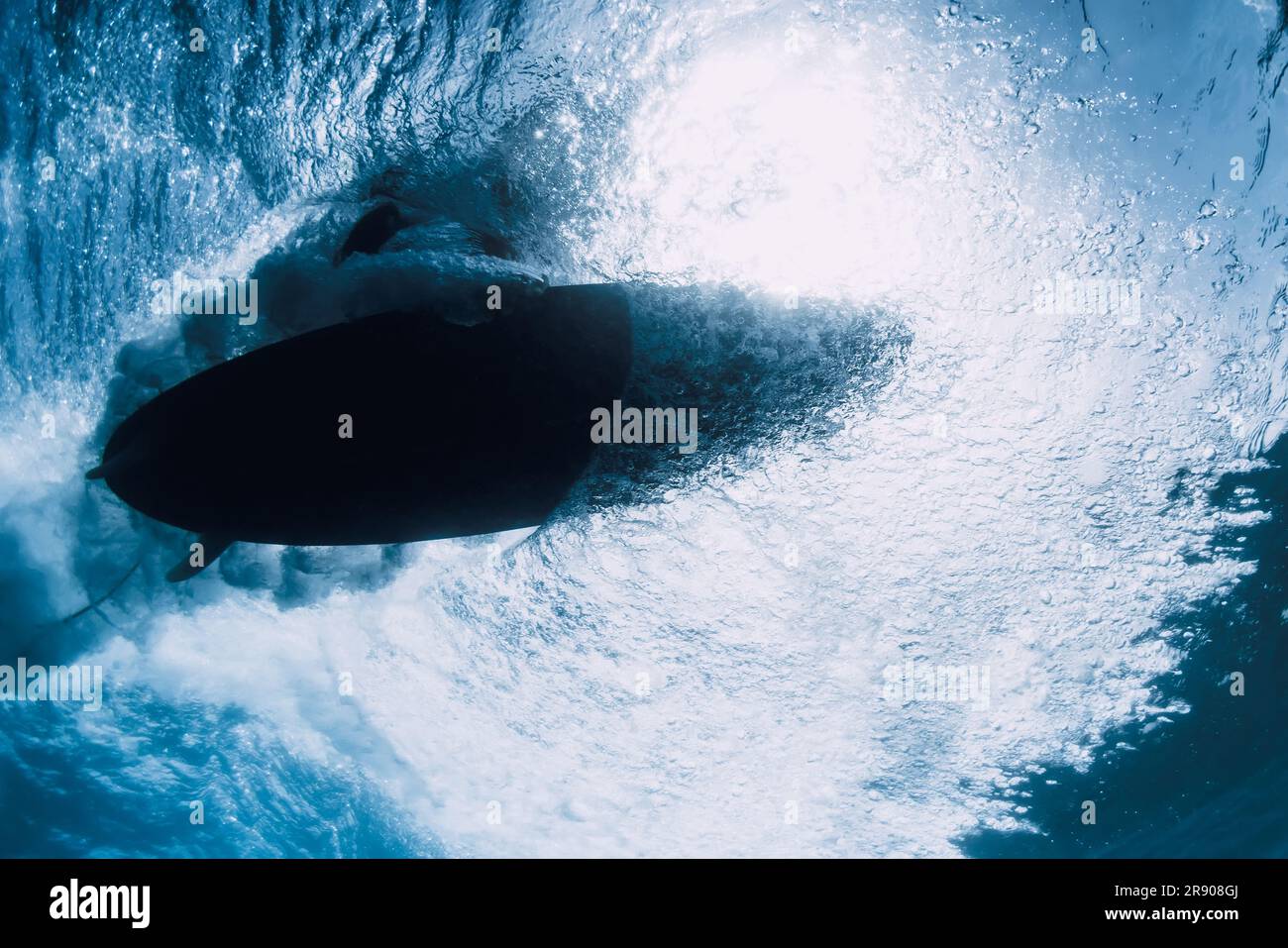 Surfer on surfboard in ocean underwater view. Crashing wave and ...